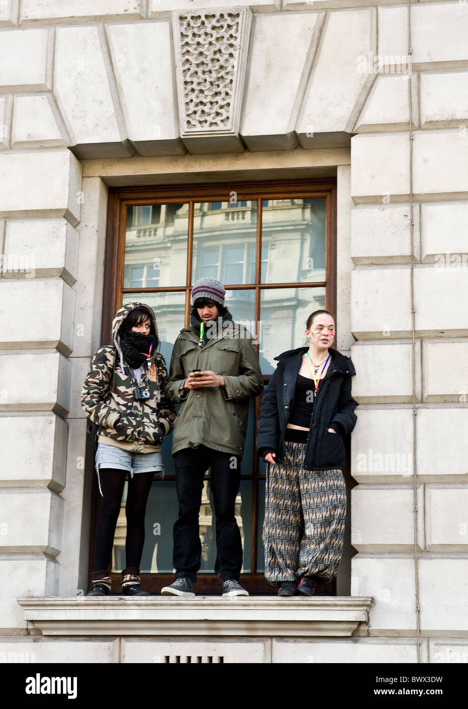 Three young people standing on a window during a demonstration in ...