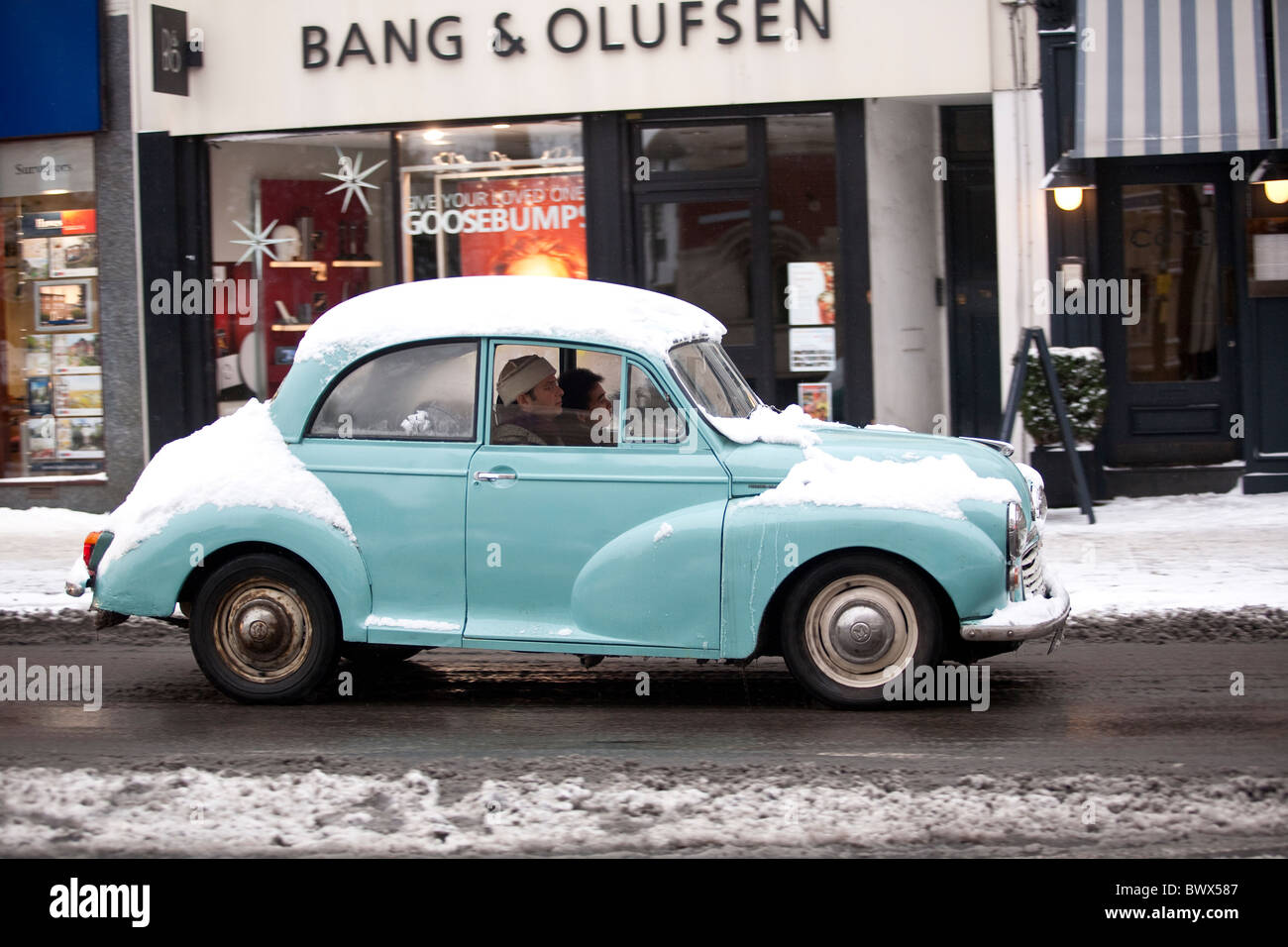 A couple drive a Morris Minor through Wimbledon Village, in the early ...