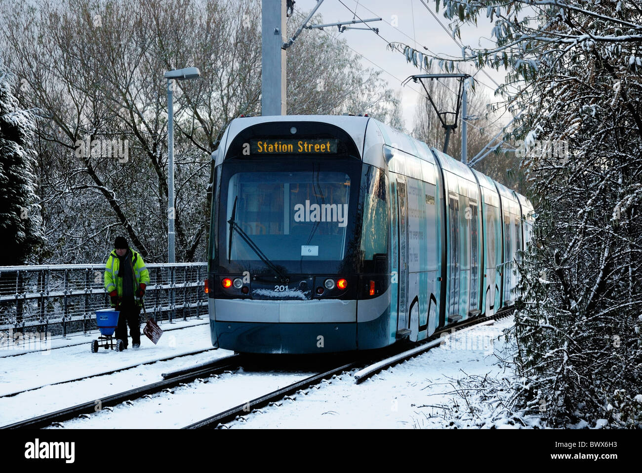 man gritting tram platform stop snow Nottingham uk Stock Photo - Alamy