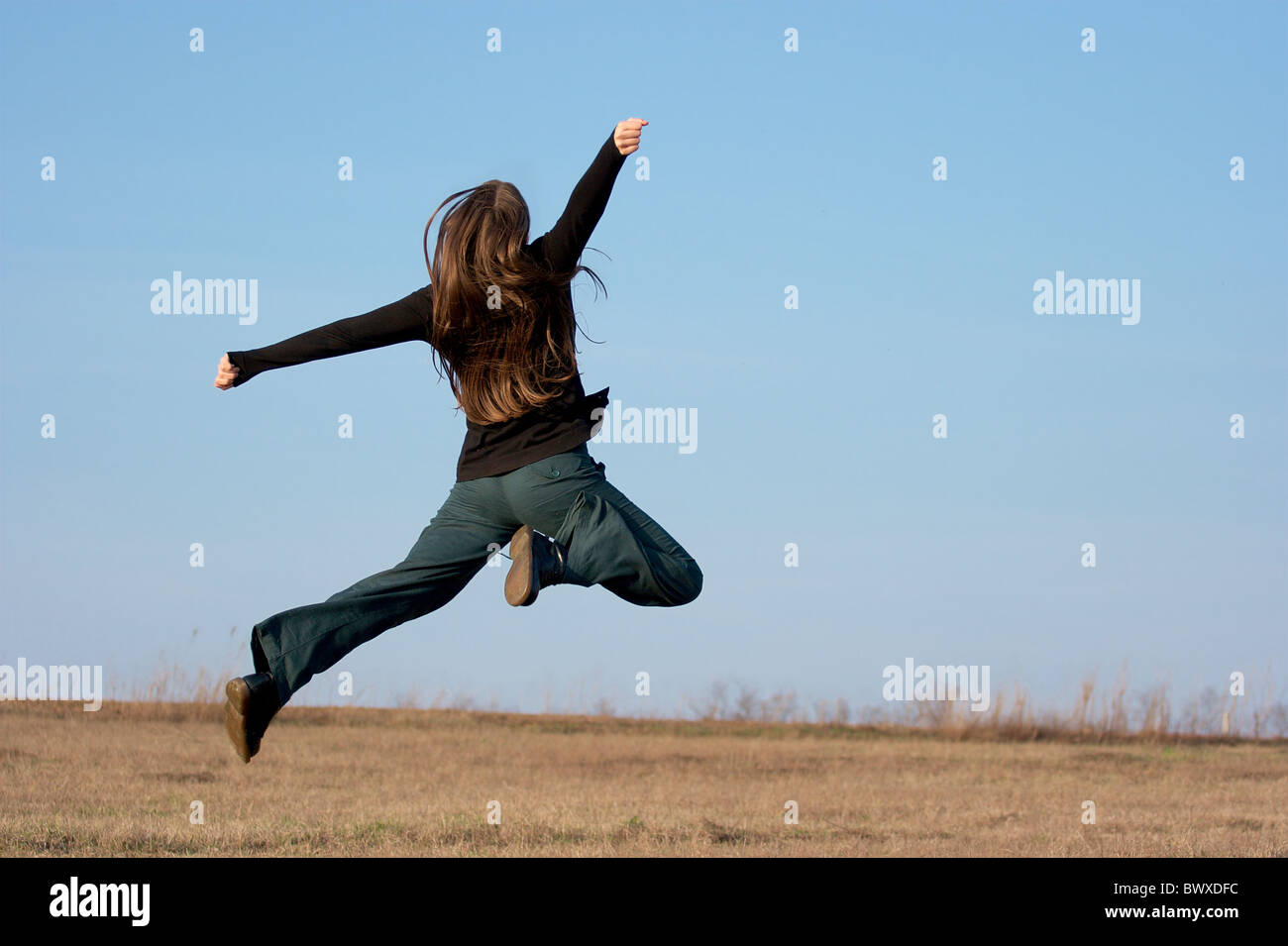 Happy girl jumping around on dry field Stock Photo - Alamy