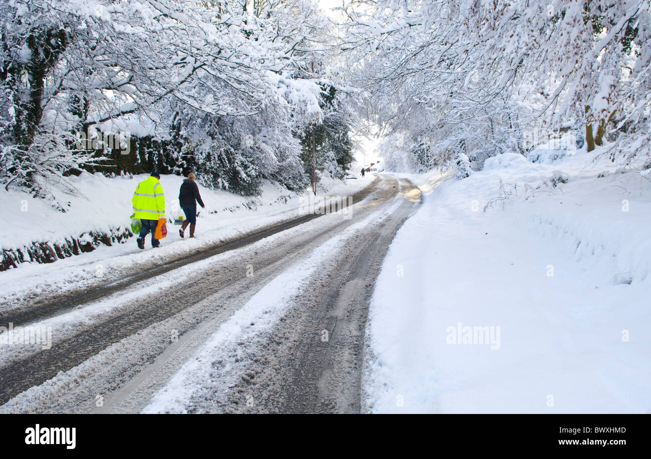 Man and woman walking along a snow covered pavement after a heavy snow ...