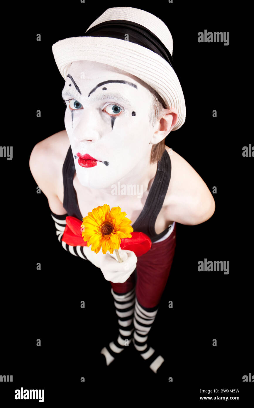 Funny mime in white hat with a bouquet of flowers on a black background ...
