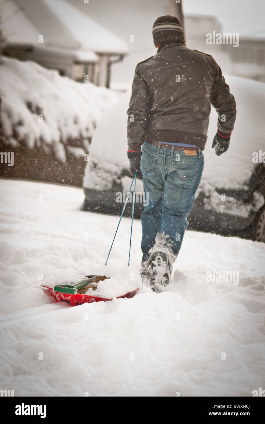 Man pulling a sledge with spade and grit Stock Photo - Alamy