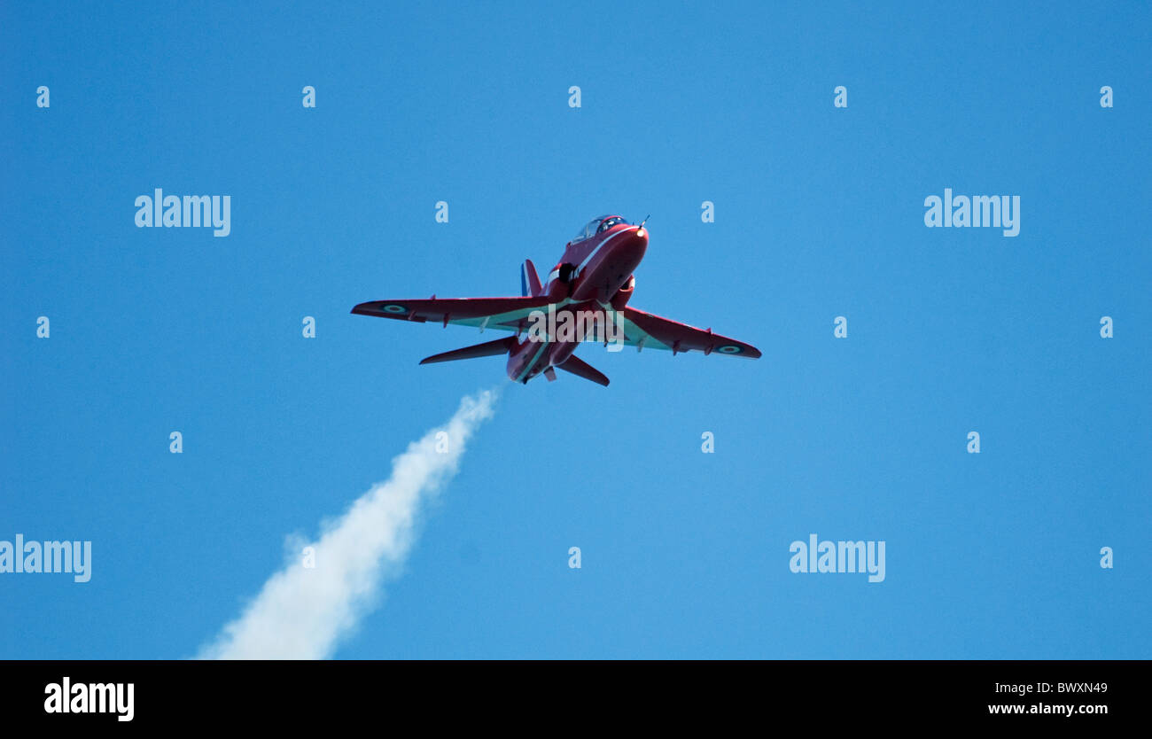 Single Red Arrows Hawk RAF in flight trailing smoke - blue sky backdrop ...