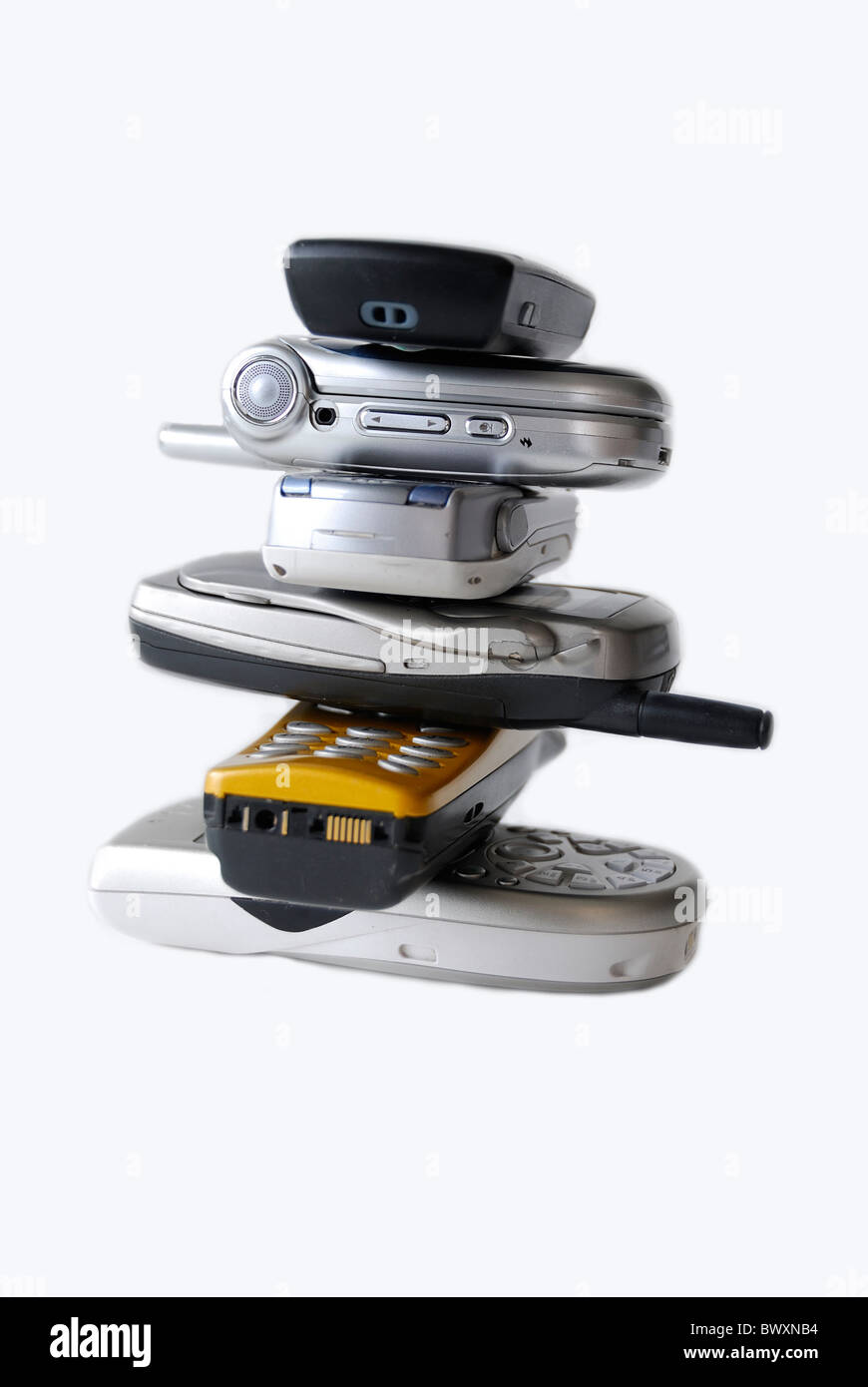 A stack of six different types of mobile phones isolated on a white ...