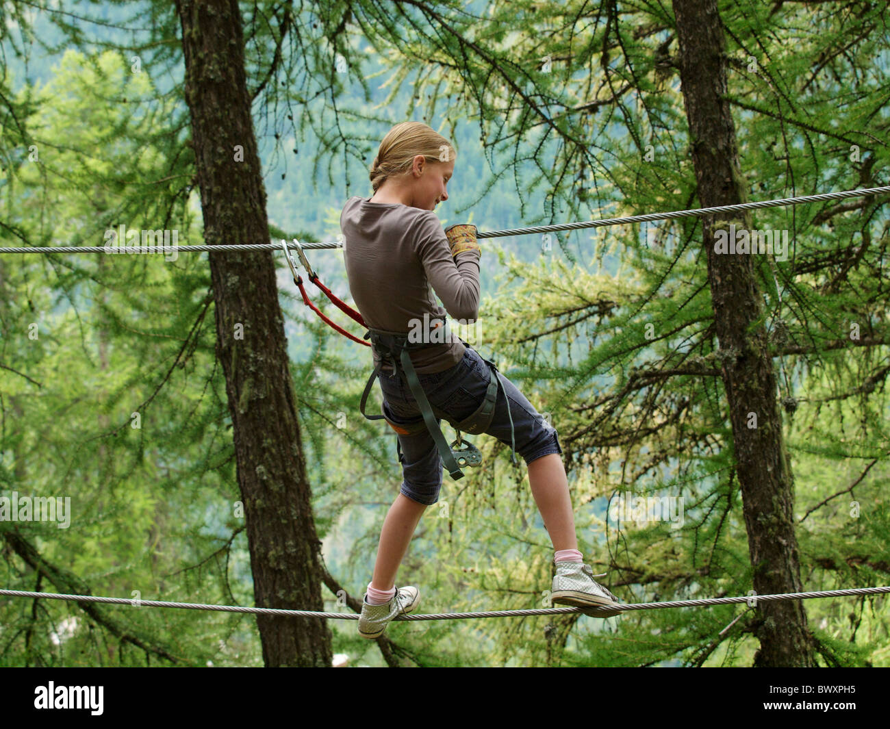 Girl standing on steel cable in climbing park in Les Orres, French Alps ...