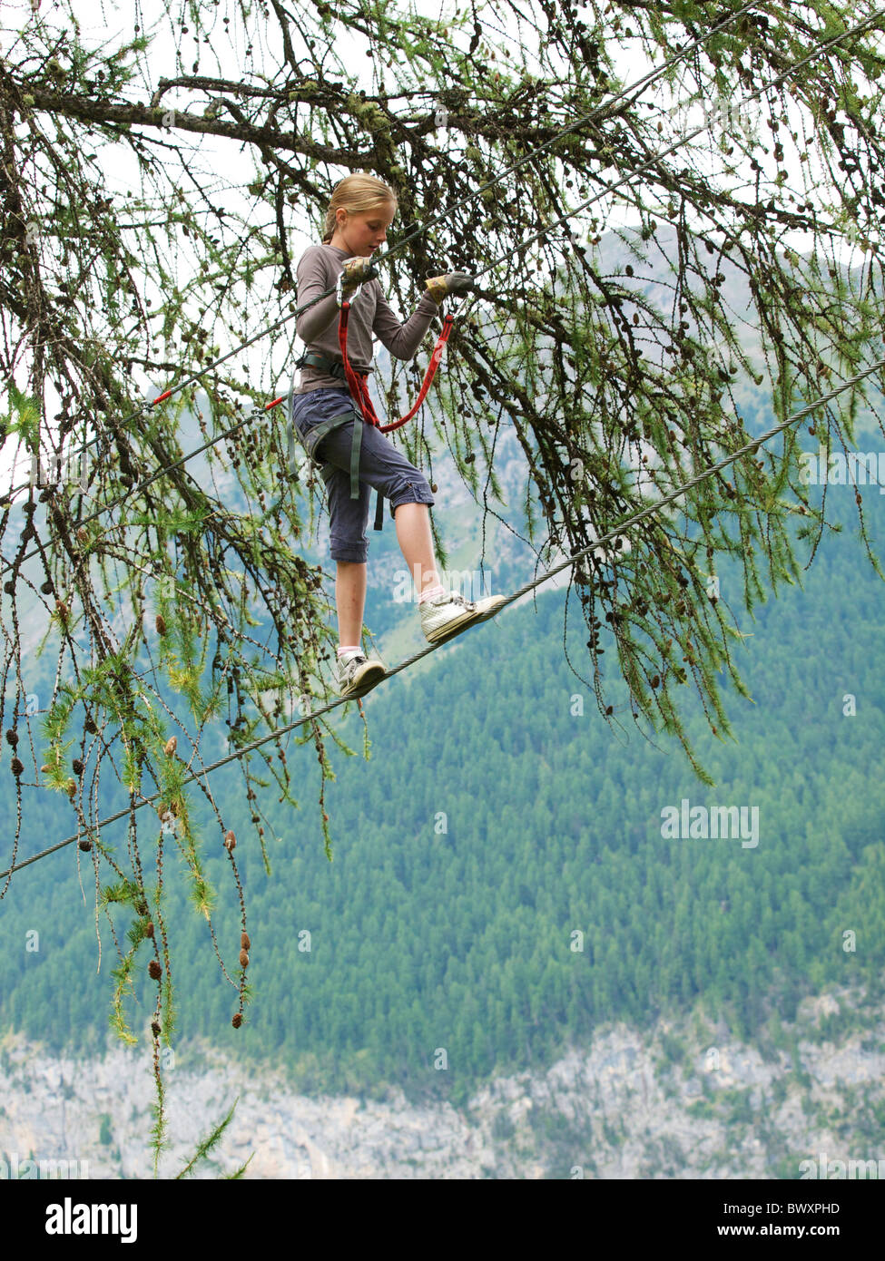 Girl standing on steel cable in climbing park in Les Orres, French Alps ...