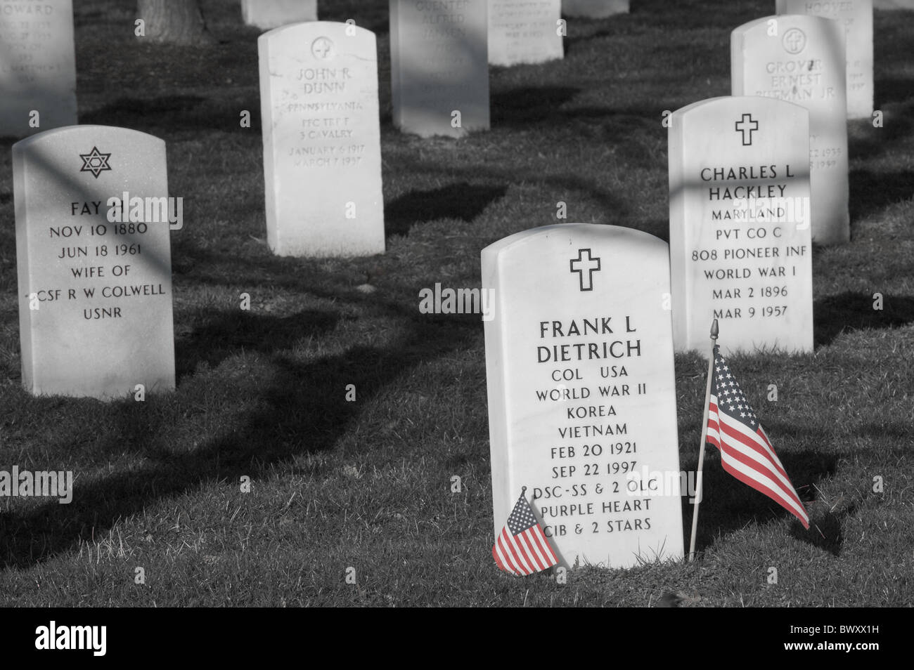 Small American flags stand next to a gravestone in Arlington National ...