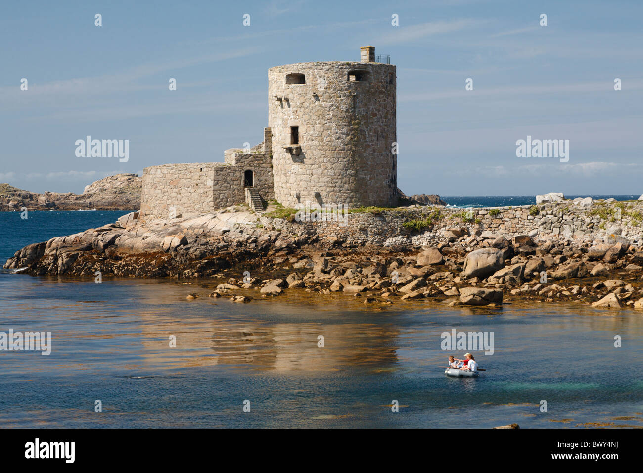 A family in a small boat in front of Cromwell's castle Tresco Isles of ...