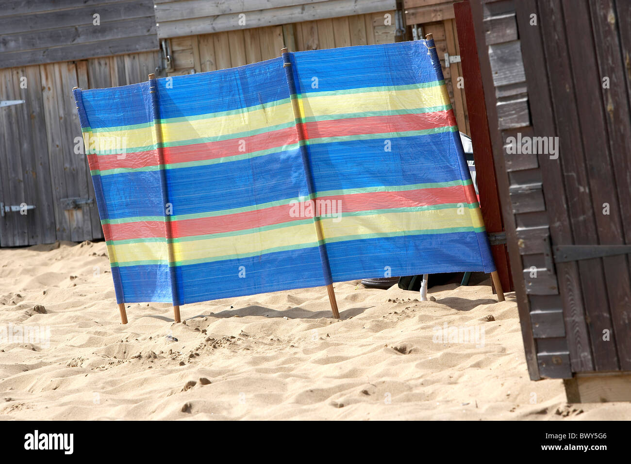 colourful wind break on sandy beach with beach huts in background Stock ...