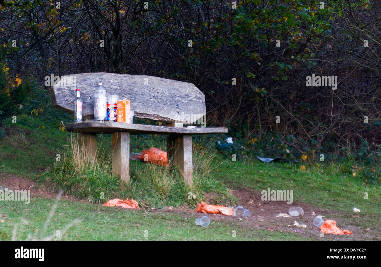 Wooden country park bench covered in and surround by litter waste and ...