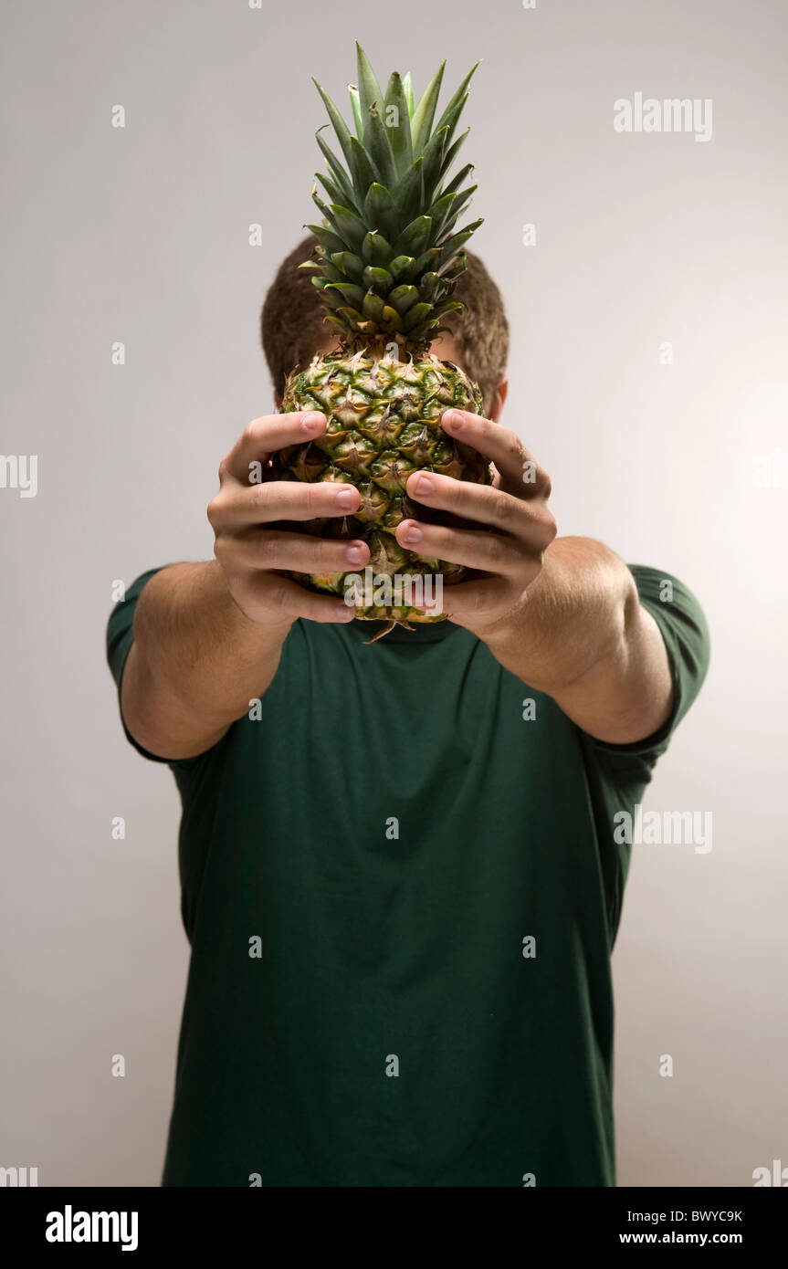 Man holding a pineapple in front of his face Stock Photo - Alamy