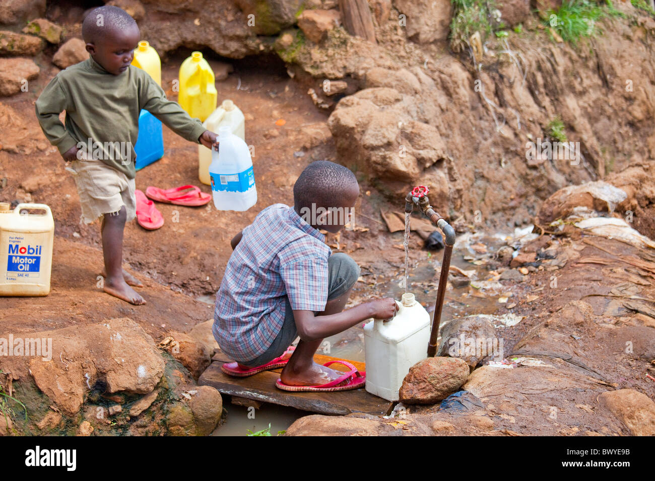 Boys filling containers with water from a tap in the Kibera slums ...