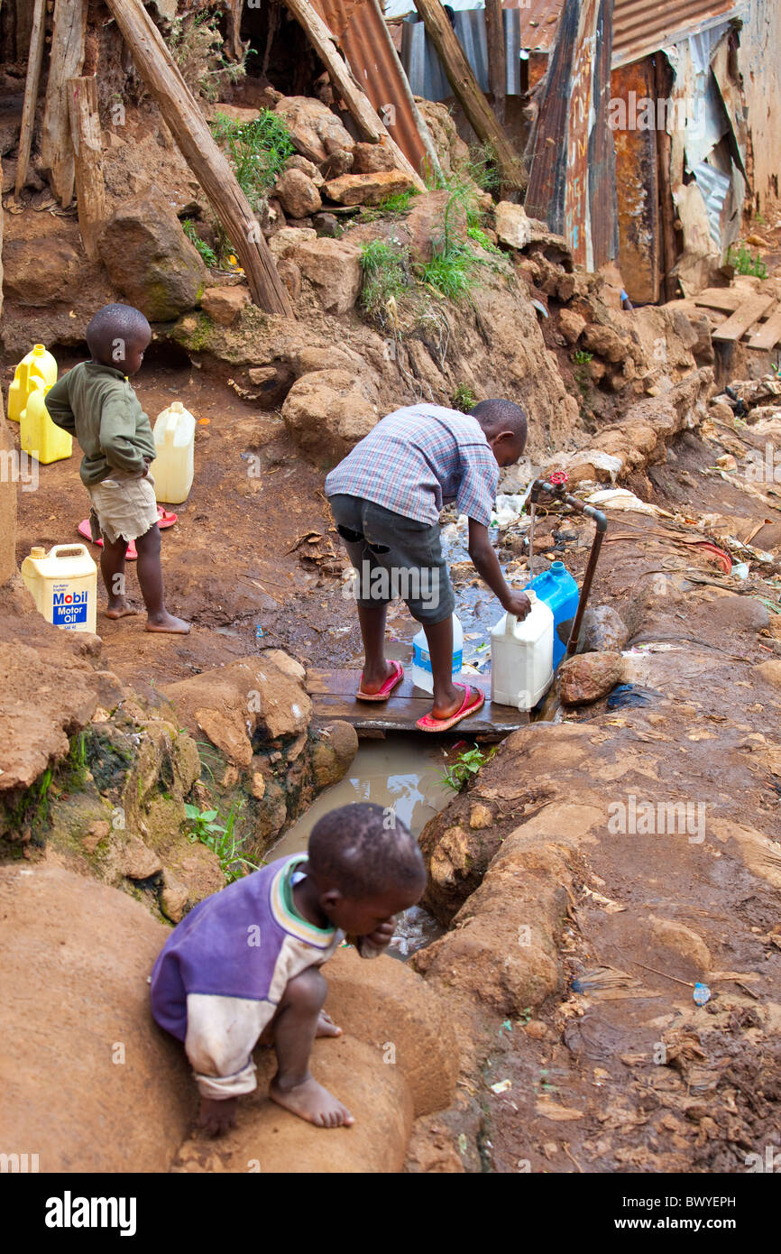 Boys filling containers with water from a tap in the Kibera slums ...