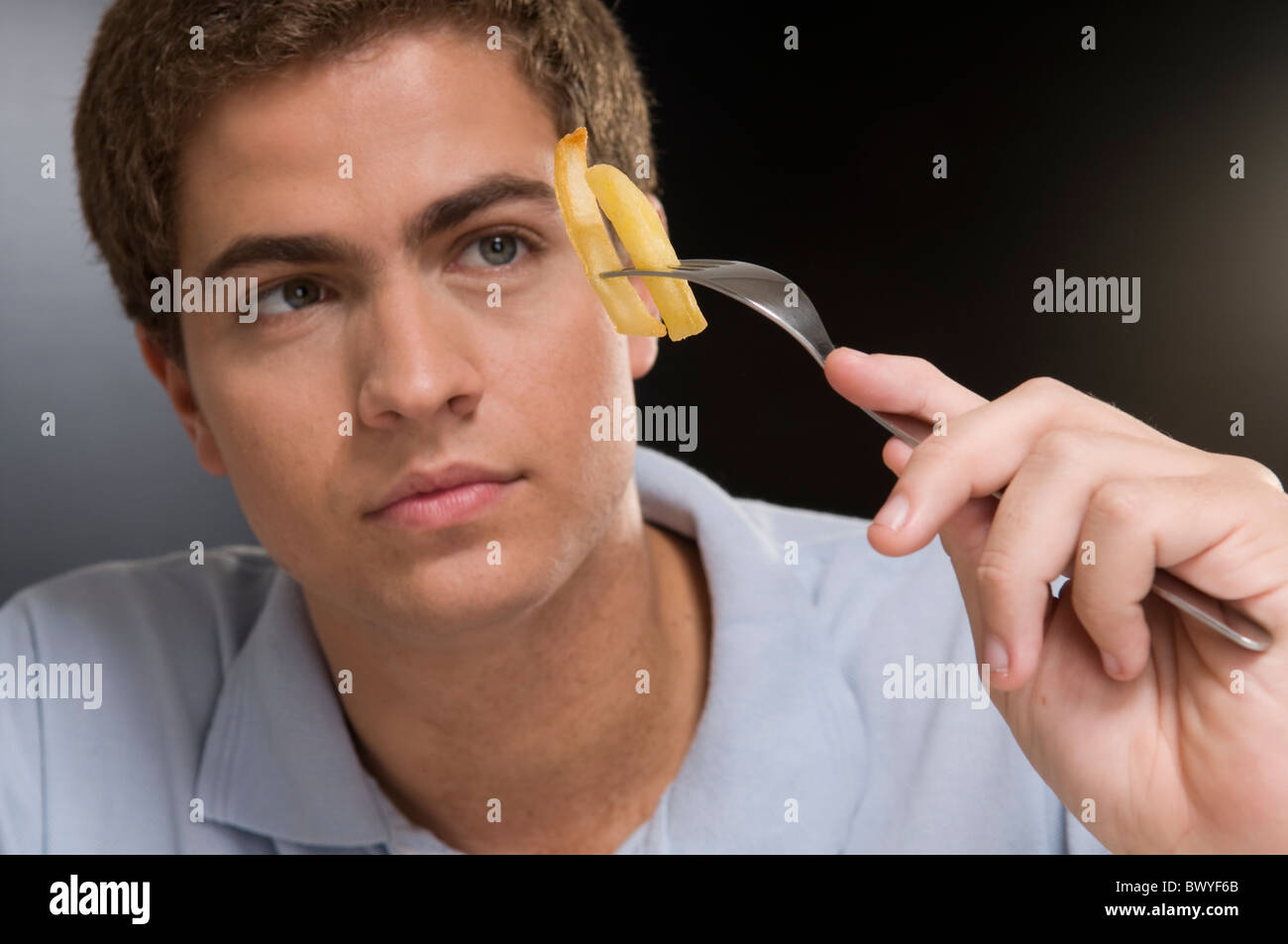 Man holding a fork with fries Stock Photo - Alamy