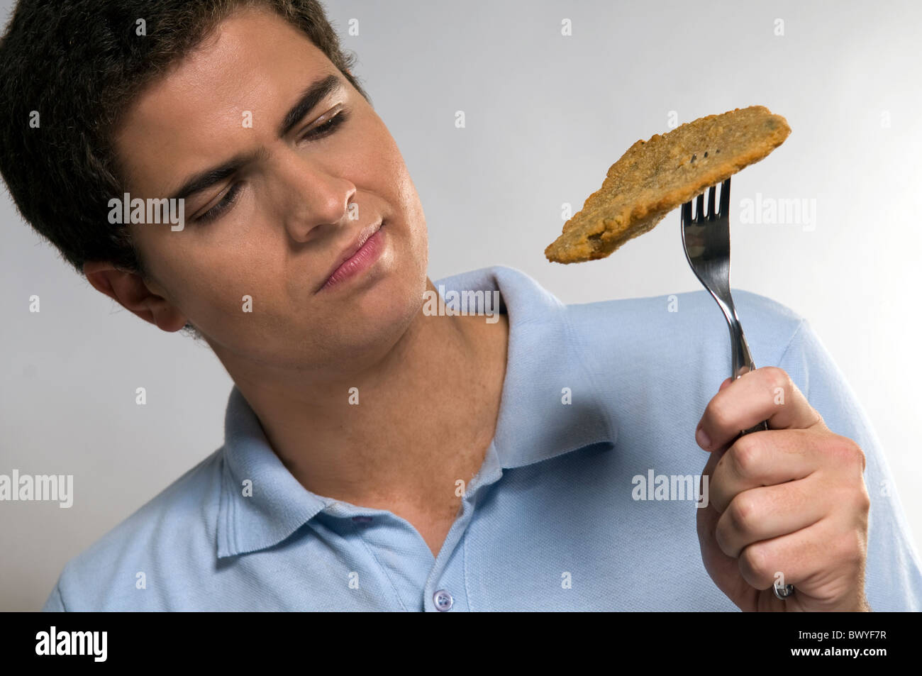 Man holding a fork with breaded steak Stock Photo - Alamy