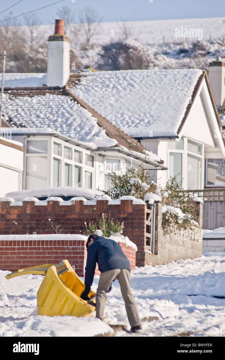 Elderly man gritting his road in the snow Stock Photo - Alamy