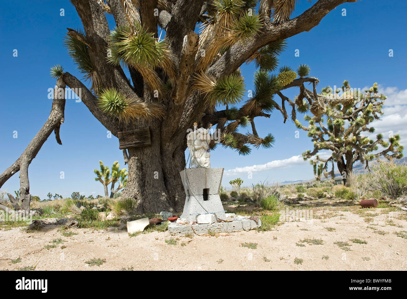 Praying winged angel carved from stone decorated with necklace's and ...