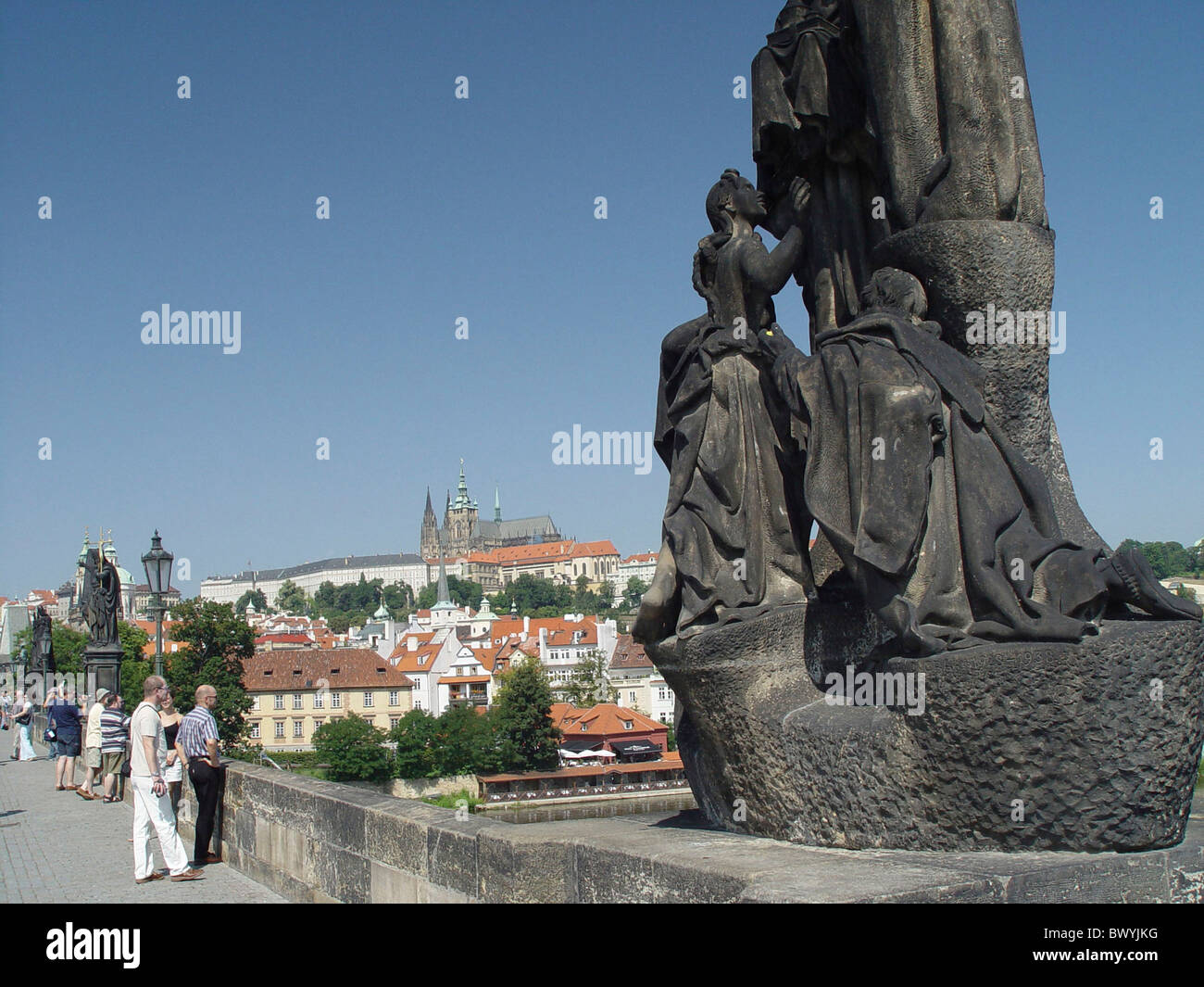 Hradcany Charles bridge pedestrian passerby Prague Prague castle sculpture statue tourist ...