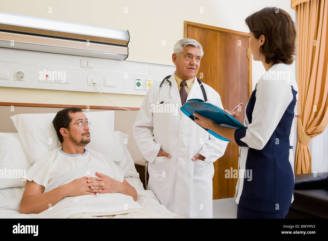 Doctor and nurse talking with patient in hospital room Stock Photo - Alamy