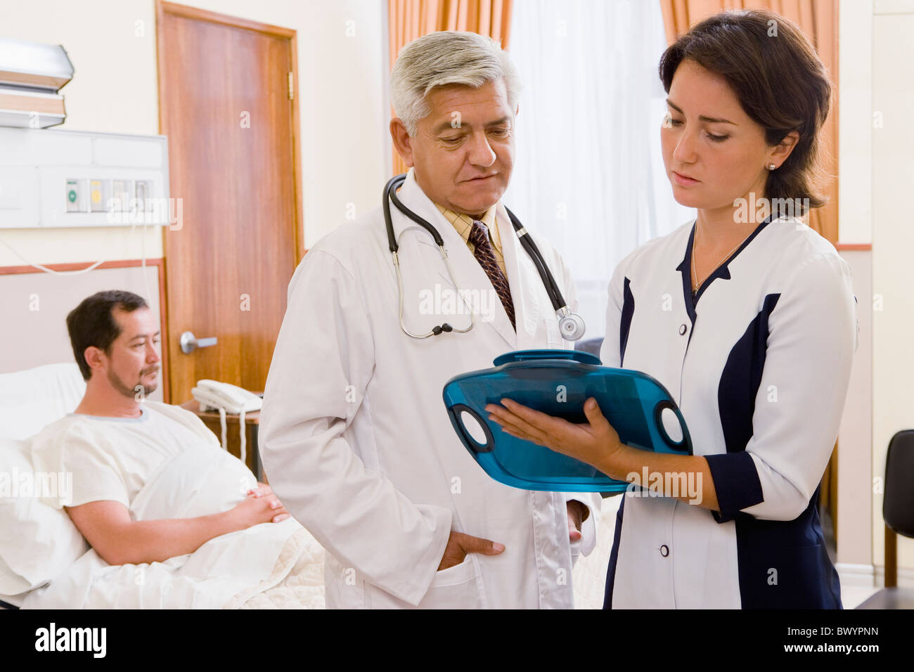Doctor and nurse discussing patient in hospital room Stock Photo - Alamy