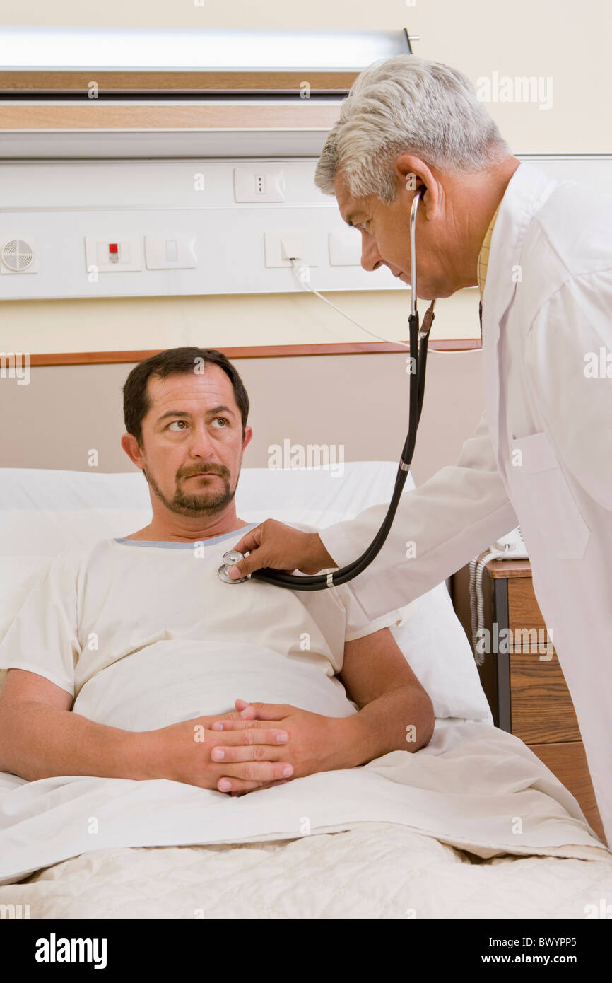 Doctor listening to patient's breathing in hospital room Stock Photo ...