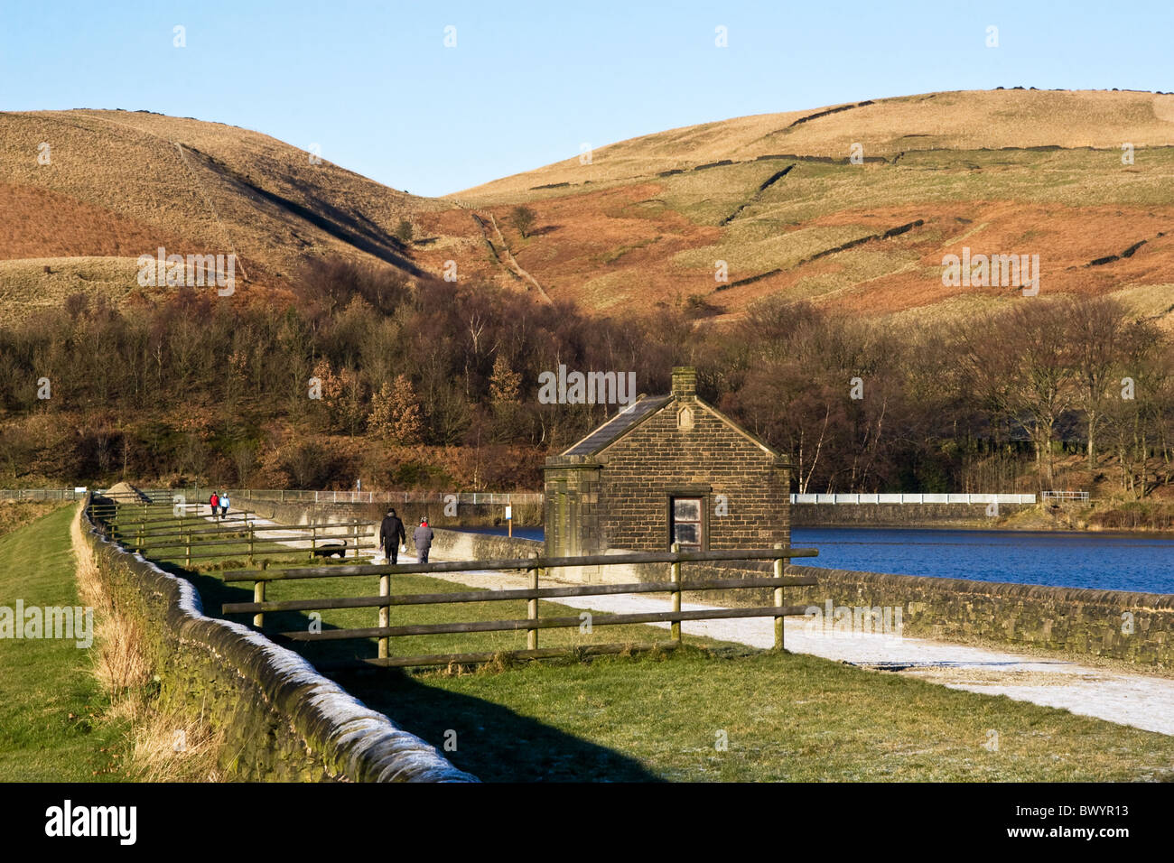 Walkers on dam of Piethorne reservoir, near Milnrow, South Pennines, UK ...