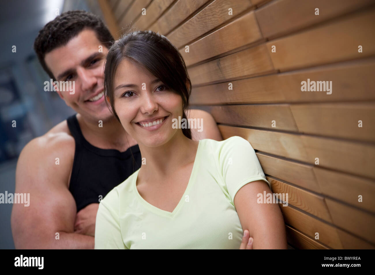 Couple leaning against wooden wall Stock Photo - Alamy