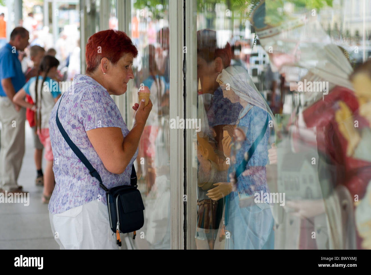 A woman looking at a window of a store selling devotional articles ...