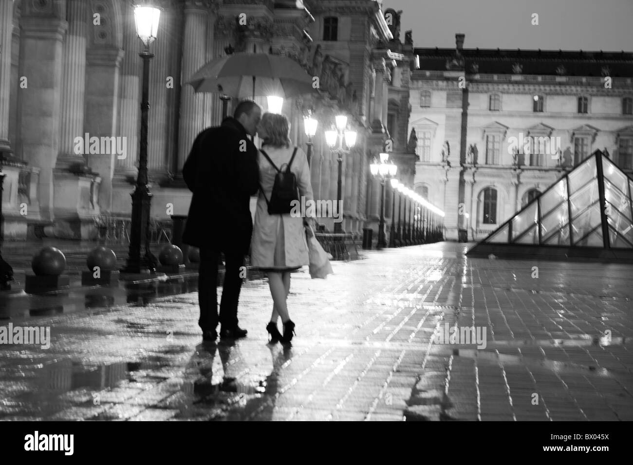 Caucasian couple kissing in rain at night at the Louvre Stock Photo - Alamy