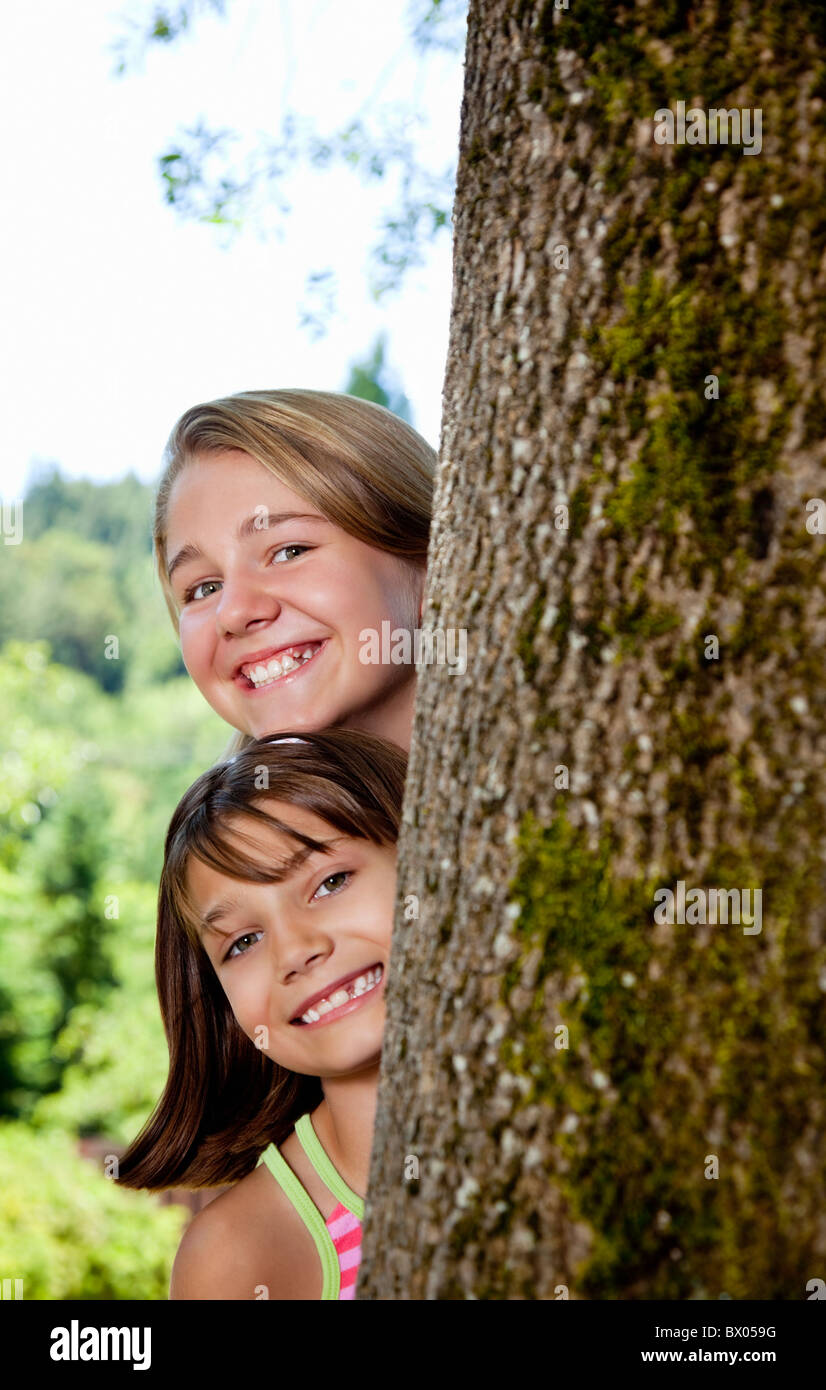 Smiling Caucasian girls near tree trunk Stock Photo - Alamy