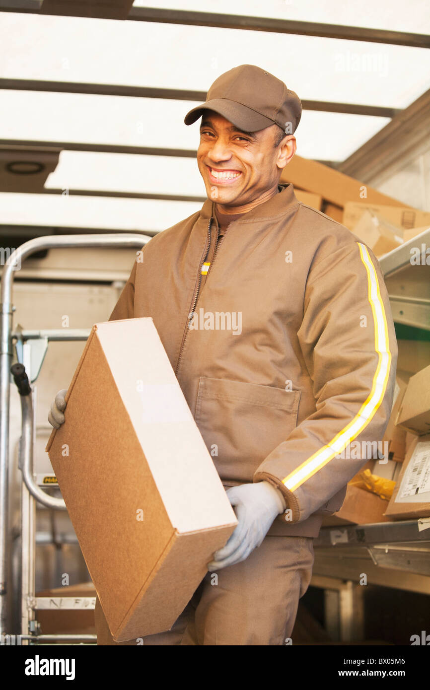 Smiling Hispanic delivery man holding cardboard box Stock Photo - Alamy
