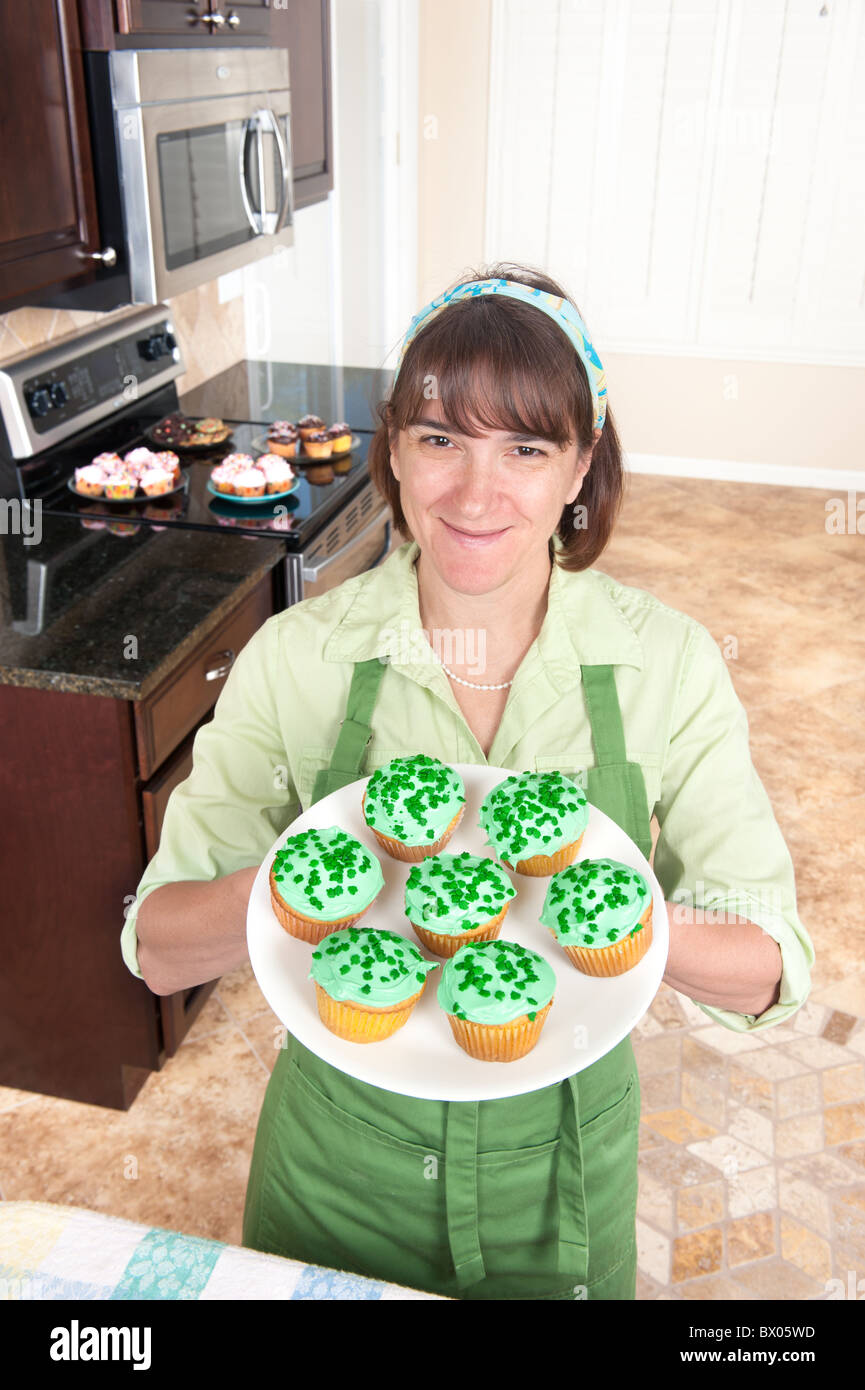A homemaker displays a set of green cupcakes with clover sprinkles in ...