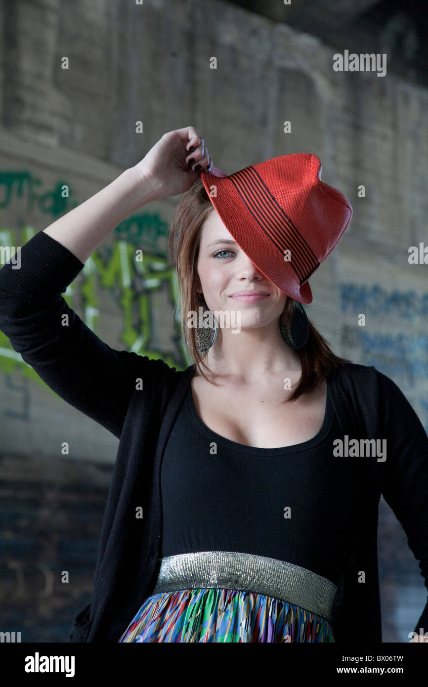 Smiling Caucasian teenage girl tipping hat on head Stock Photo - Alamy