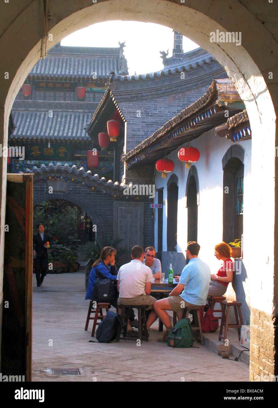 Caucasian visitors sitting in a traditional courtyard house hotel ...
