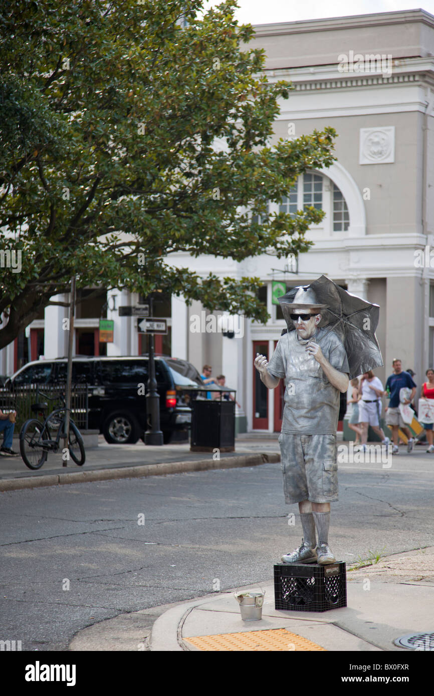 A man, painted in silver and standing still as a statue, performs for ...
