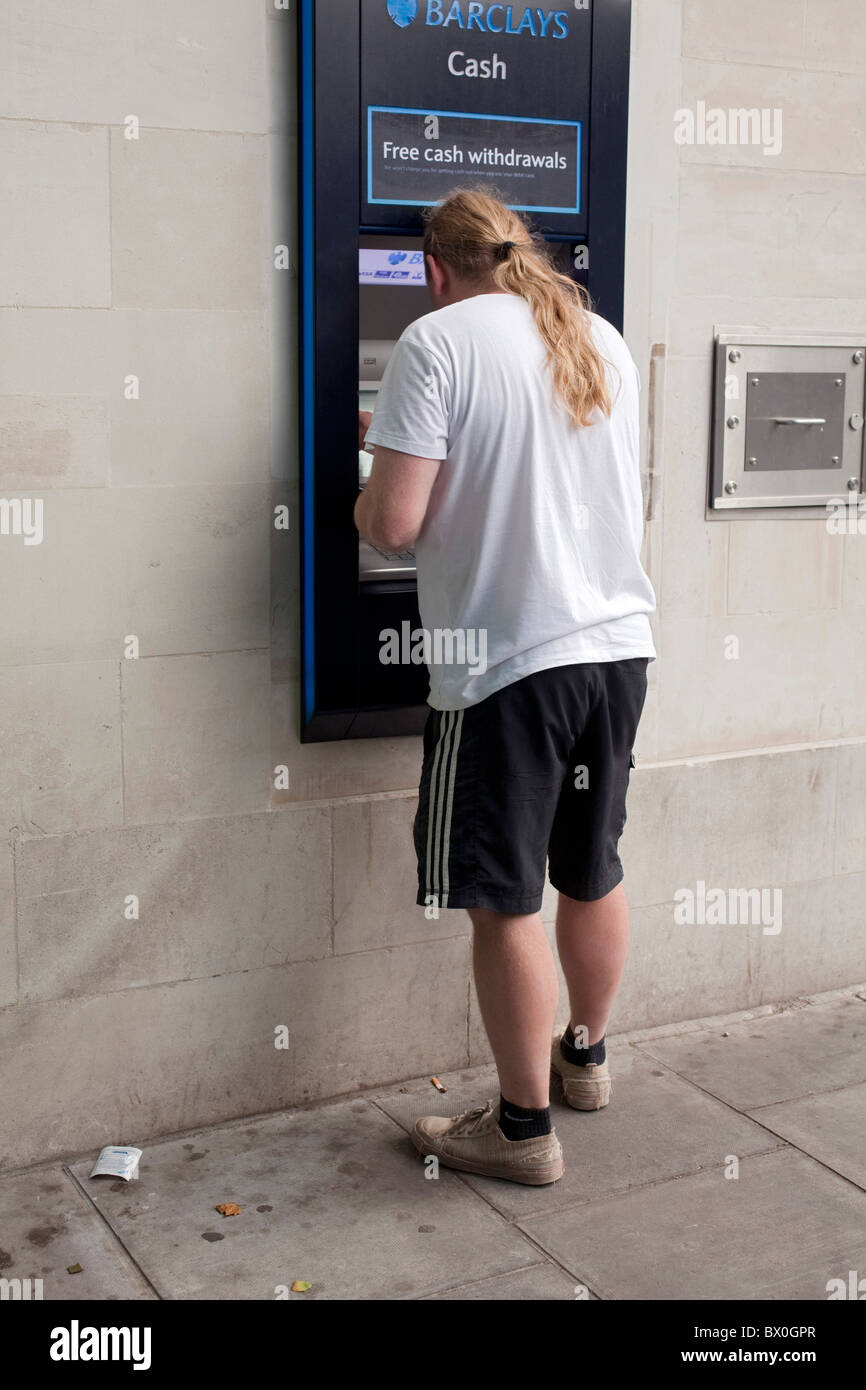 A male customer using a cash machine at Barclays Bank ATM automated ...