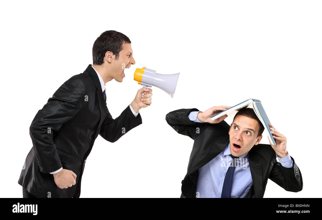 Angry businessman yelling via megaphone to a man who is covering his ...