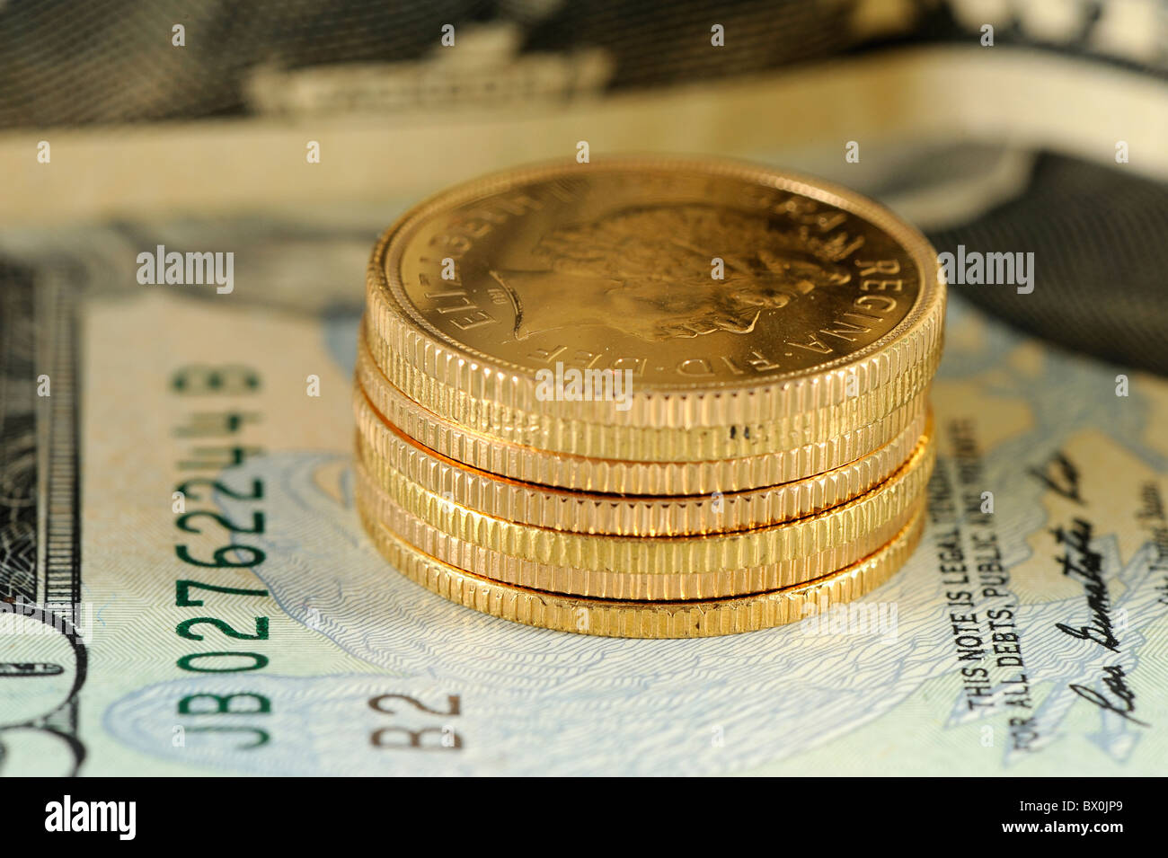 Stack of British gold sovereigns on a US twenty dollar banknote bill ...