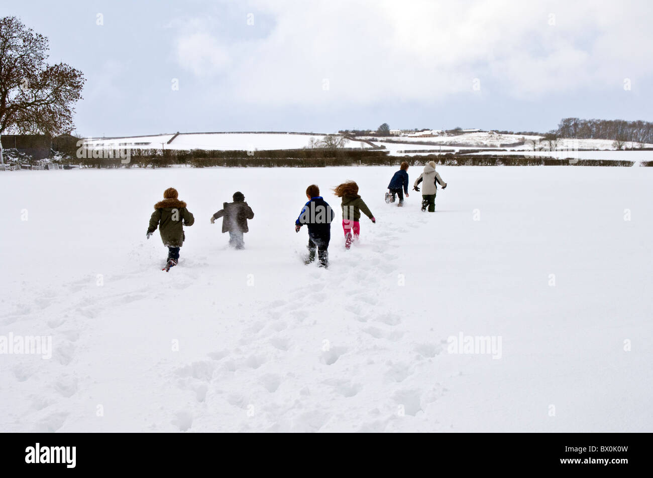 Children running in a snow covered field UK Stock Photo - Alamy