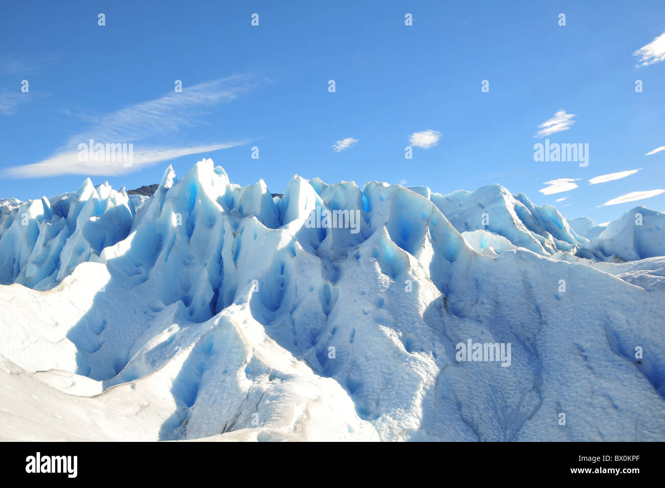 Blue sky view of a blue white ice sculptured slope, dimples, hollows ...