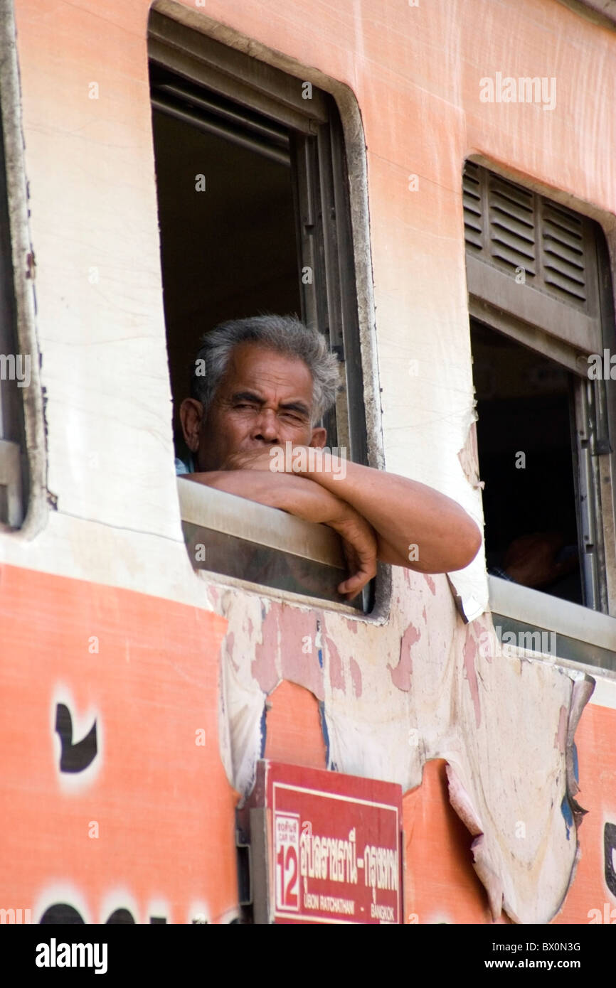 A middle aged Asian man is looking out of a train passenger car window ...