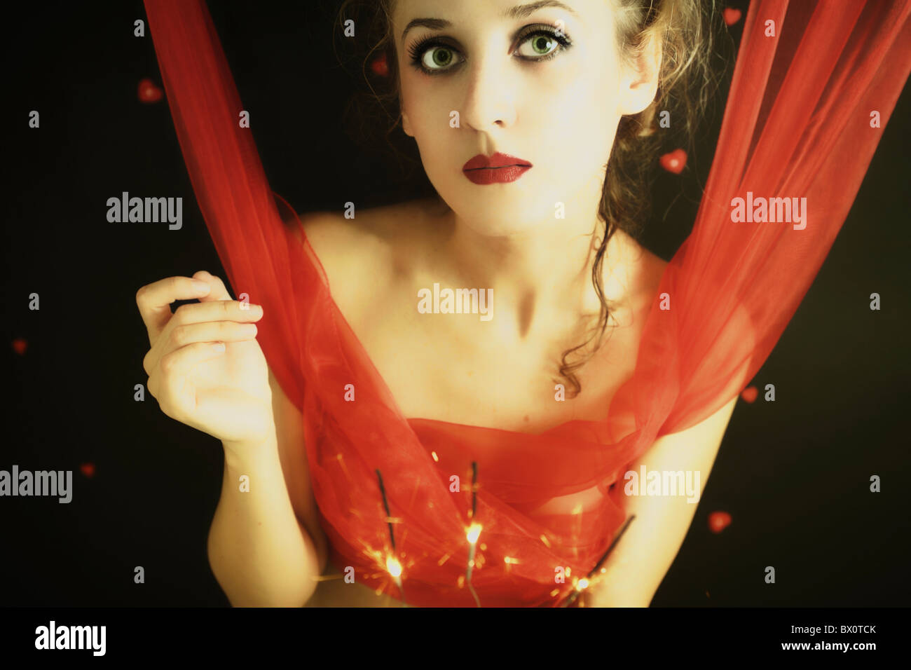 Beautiful curly blond woman with red ribbons on a black background ...