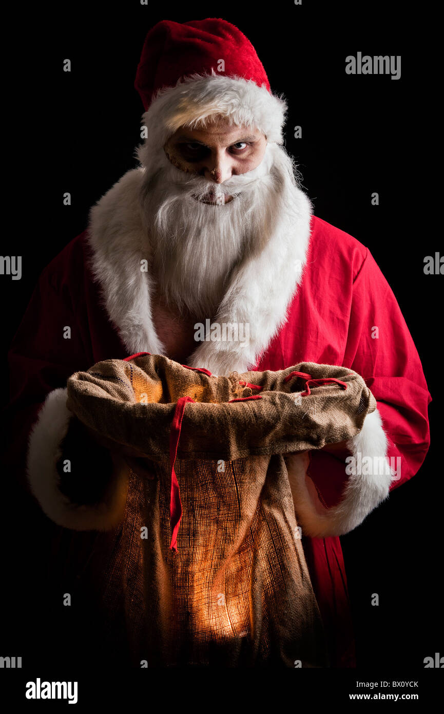 a scary looking santa holding a glowing present bag Stock Photo - Alamy