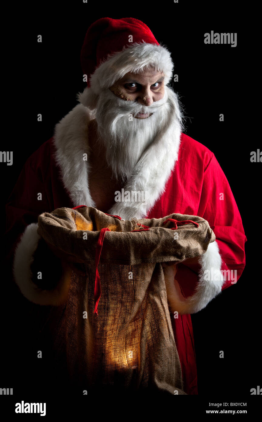 a scary looking santa holding a glowing present bag Stock Photo - Alamy