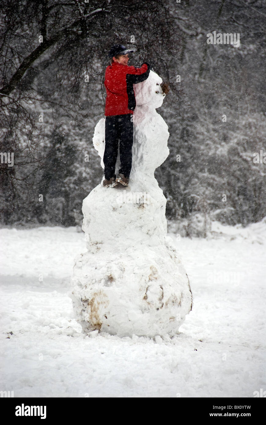 Young boy building enormous snowman in the park Stock Photo - Alamy
