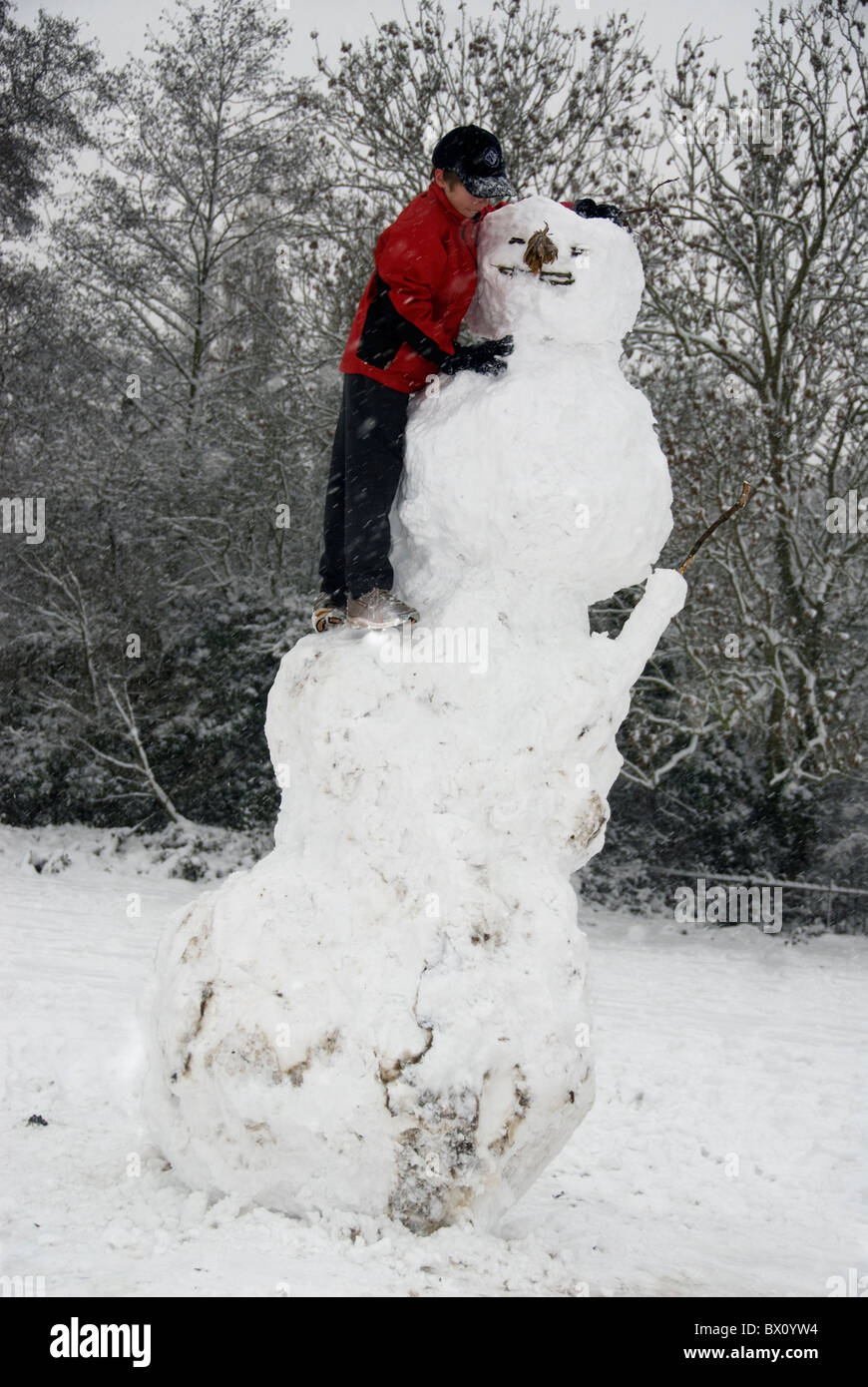 Young boy building enormous snowman in the park Stock Photo - Alamy