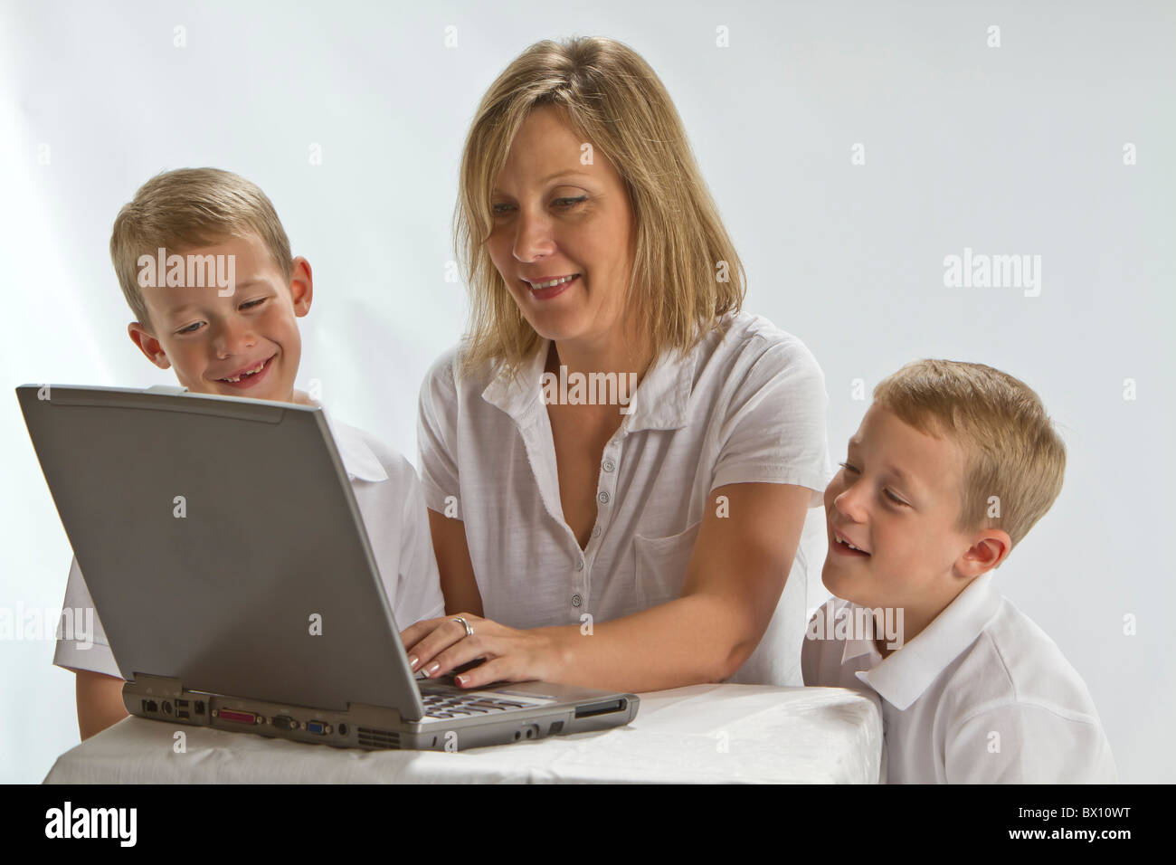 A Mom teaching 6 years old twins how to use a laptop computer Stock ...