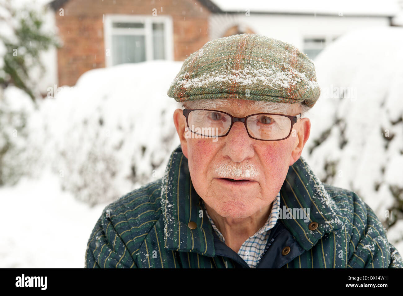 Pensioner retired Gurkha Major clearing driveway of snow Stock Photo ...