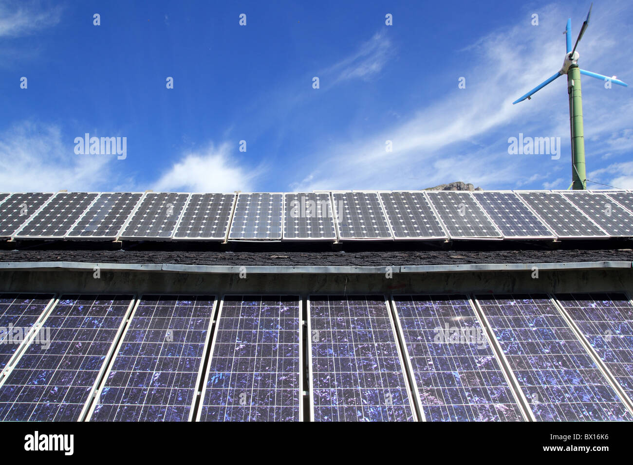 solar plates and windmill under blue sky green energy Stock Photo - Alamy